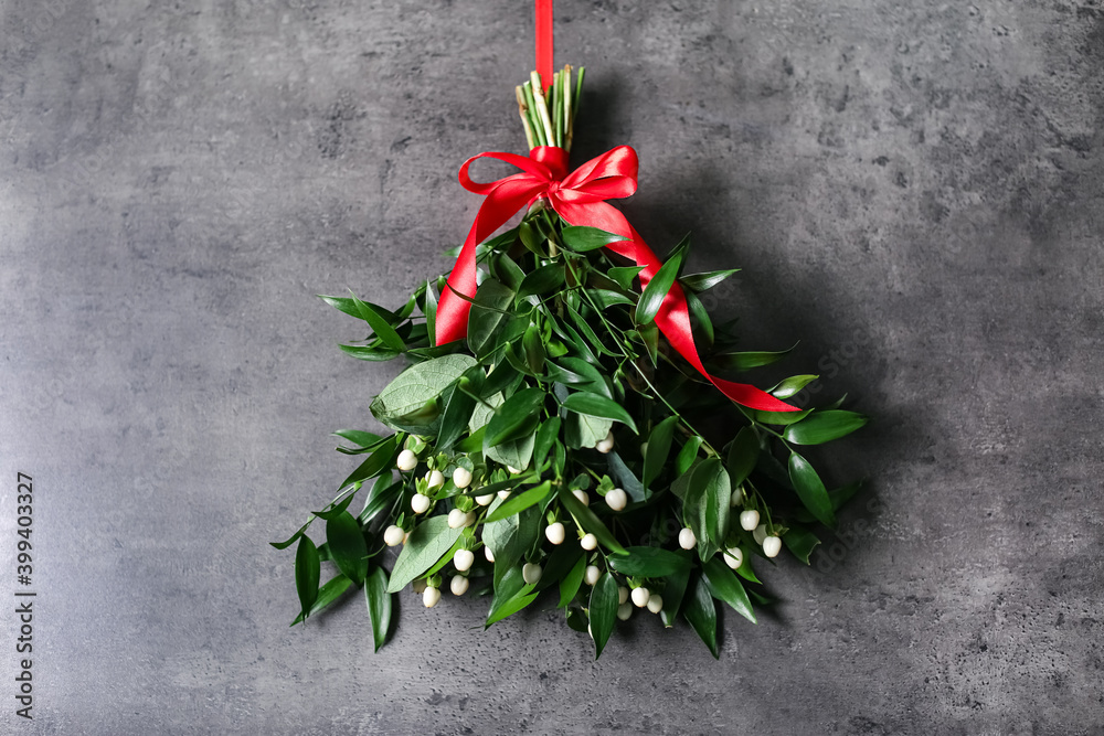 Mistletoe bunch with red bow hanging on grey wall. Traditional ...
