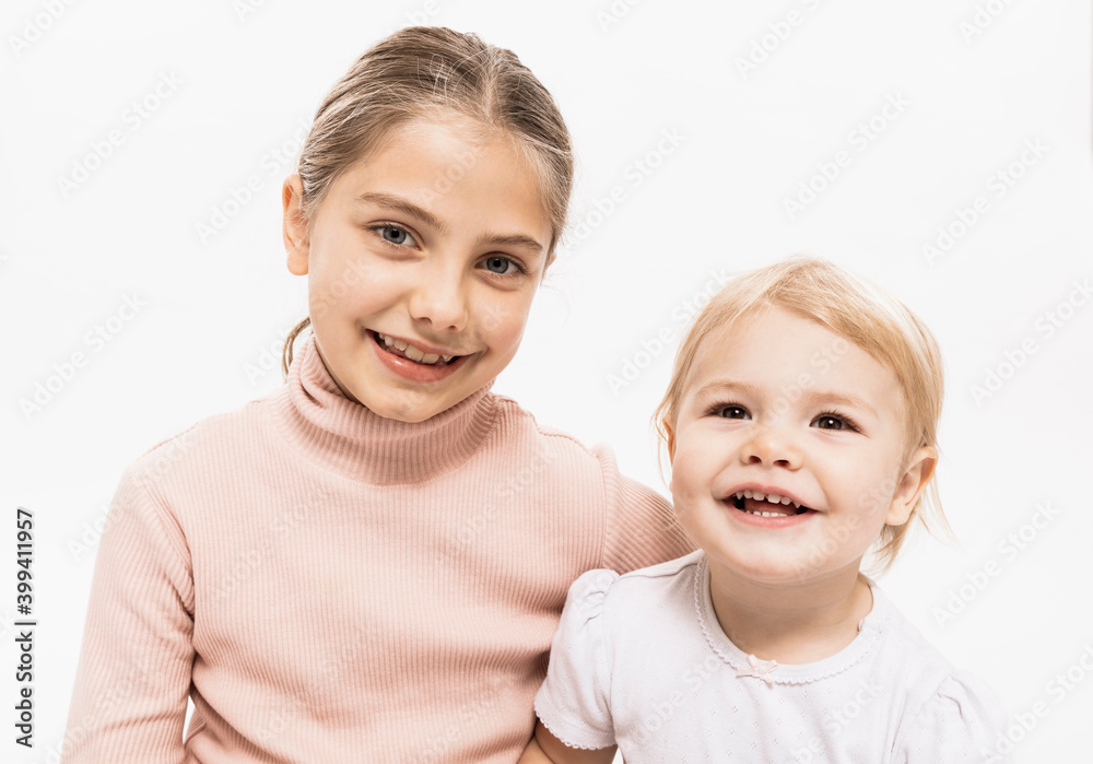 Smiling sisters sitting against white background in studio Stock Photo ...