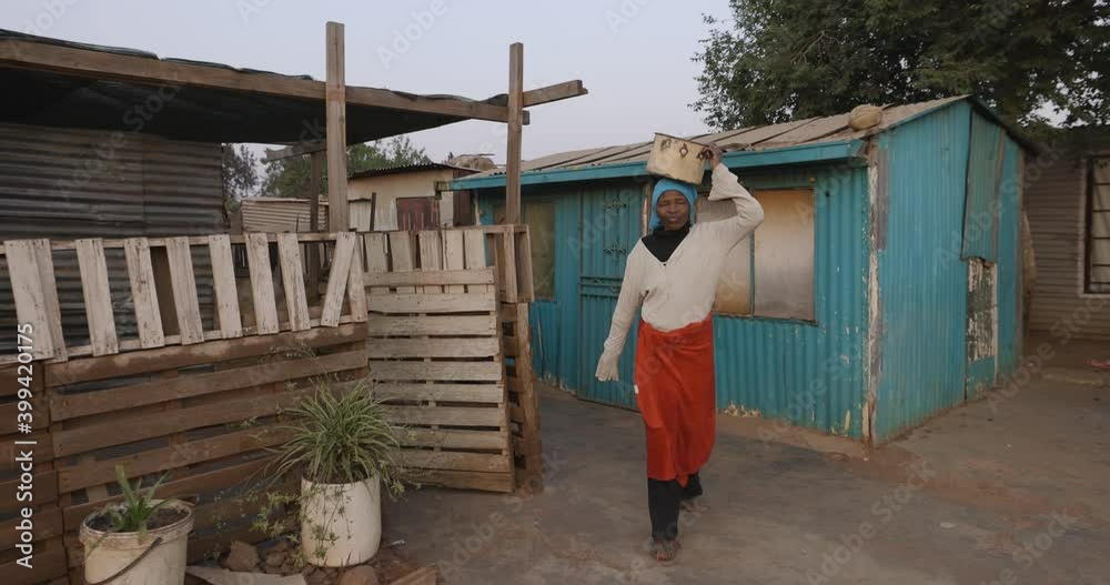 Face of poverty. A poor Black African woman walking with a rusty tin ...