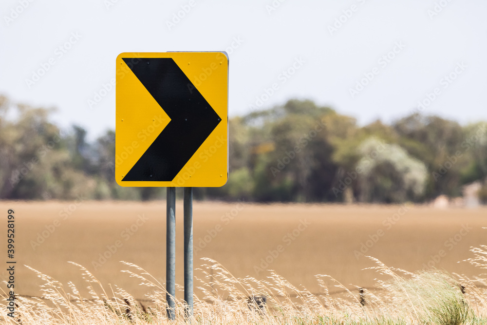 Black and yellow direction sign post on curve bend in road pointing ...