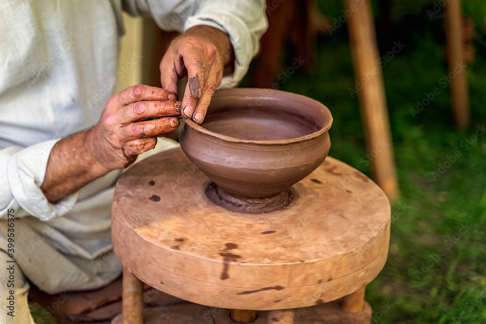 Craftsman hand making pottery from clay on potters wheel at historical ...