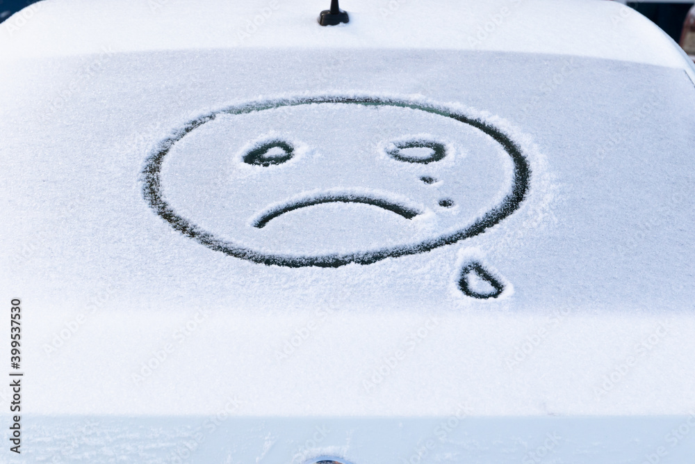 image of a crying face emoji on the snow on the back window of a car on ...