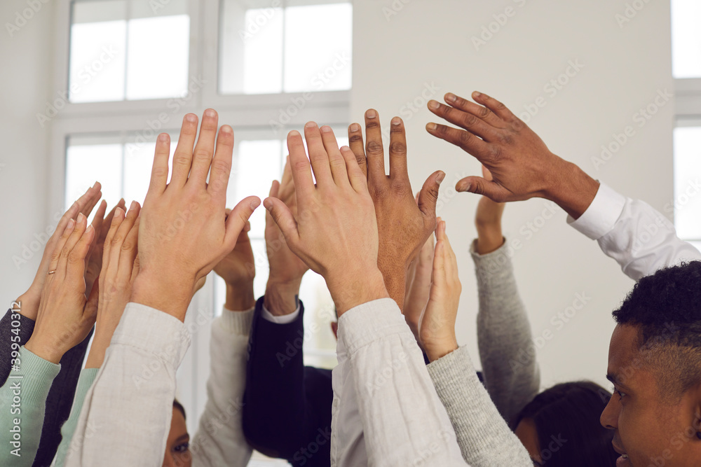 Team of multiracial people raising hands up in the air, showing ...