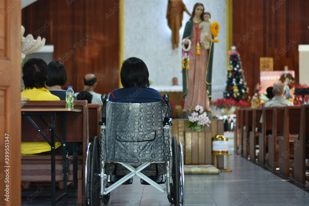 Rear view of people sitting on wheelchair in church for pray to jesus ...