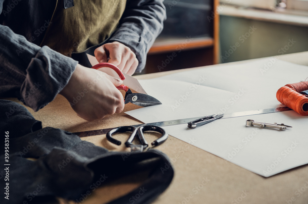 An experienced shoemaker in a shoe production workshop makes a pattern ...