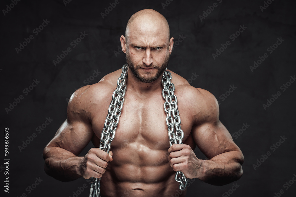 Foto de Posing in dark background powerful and hairless bodybuilder ...