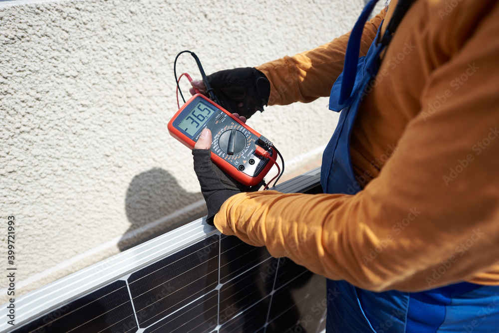Male worker installing solar photovoltaic panel system on roof of ...