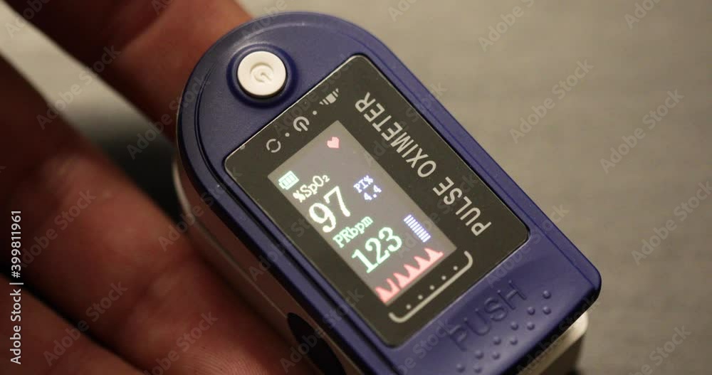 Details with the hand of a man taking his pulse and blood oxygen level ...