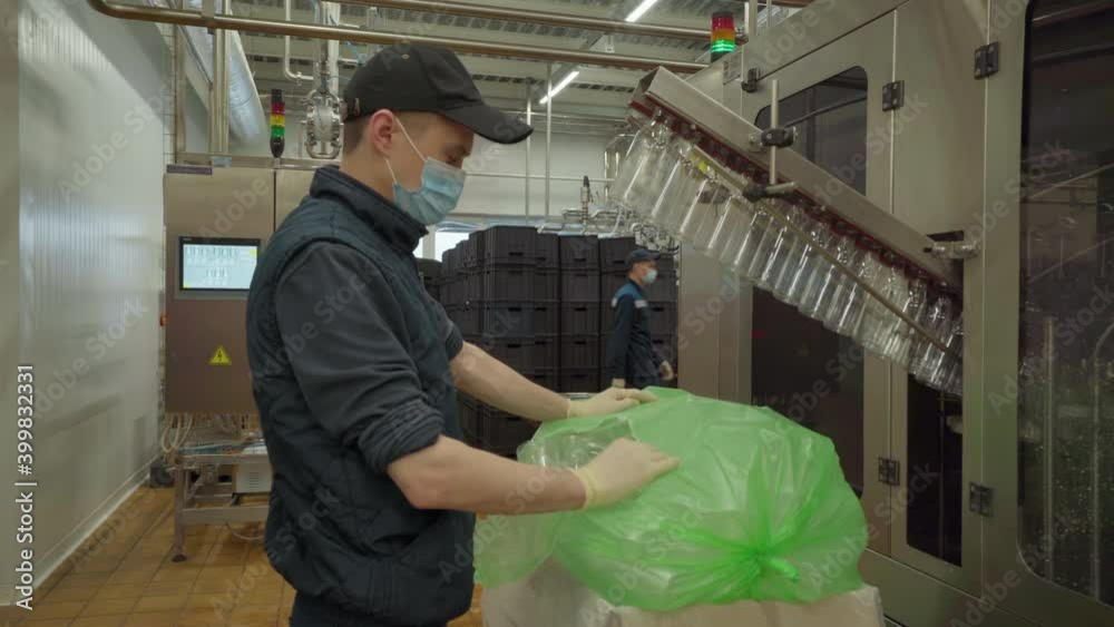 Operator is wearing black work uniform, takes bottles from a green ...