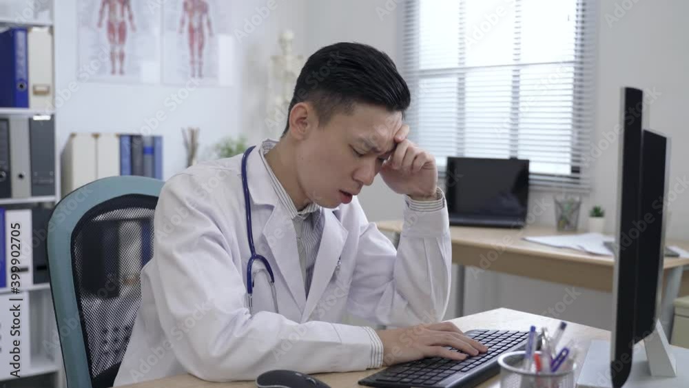asian doctor experiencing stress at work is propping head and touching ...