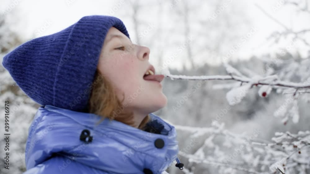 Vídeo do Stock: Curious girl licking snow from tree twigs in forest ...