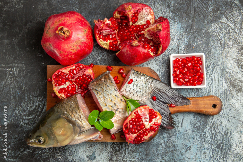 top view sliced fresh fish with pomegranates on light-dark background ...