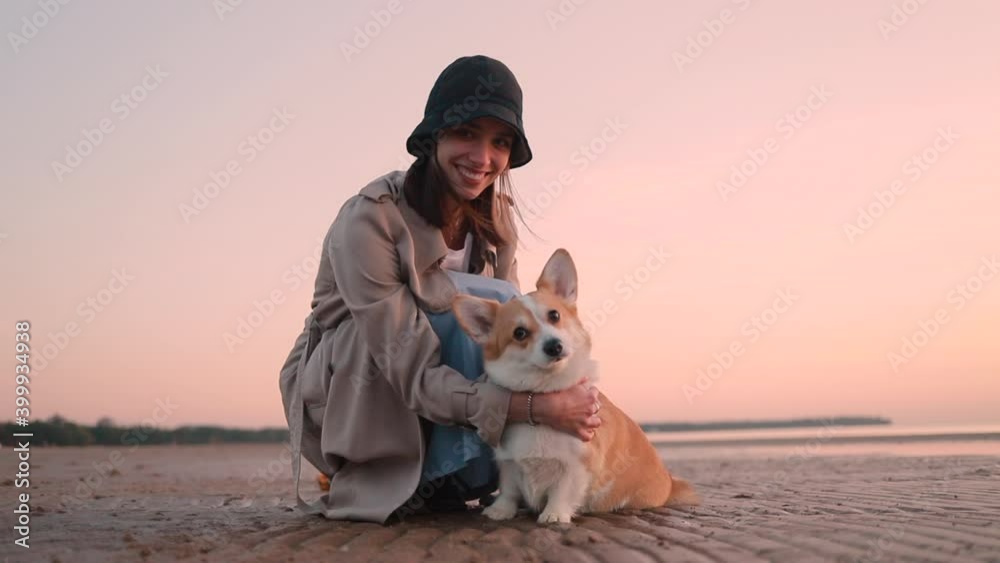 Corgi dog and woman in hat posing on beach at sunset spbi. Portrait of ...