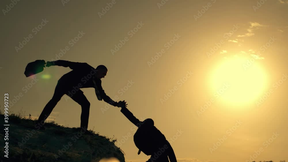 Two businessmen climb to top of mountain. Helping hand in business ...