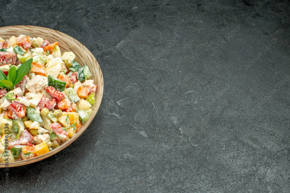 side close view of bowl of vegetable salad on the left side with green ...
