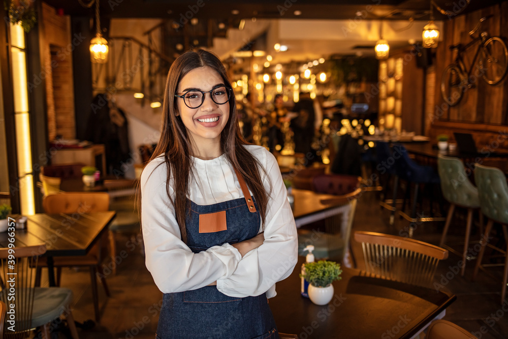 Portrait of a beautiful waitress wearing an apron, smiling at camera ...