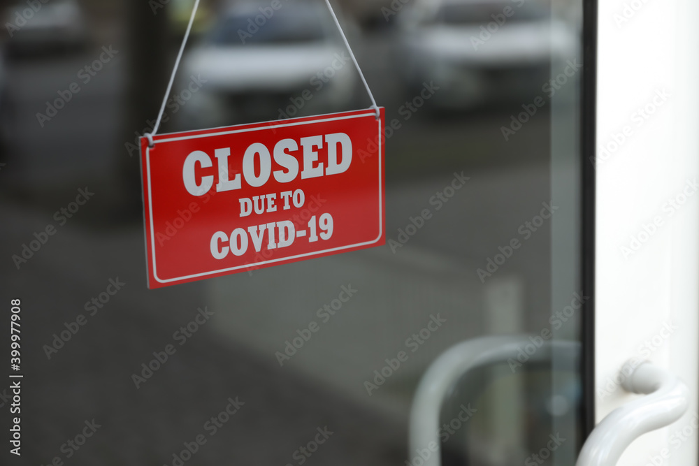 Red sign with words "Closed Due To Covid-19" hanging on glass door ...