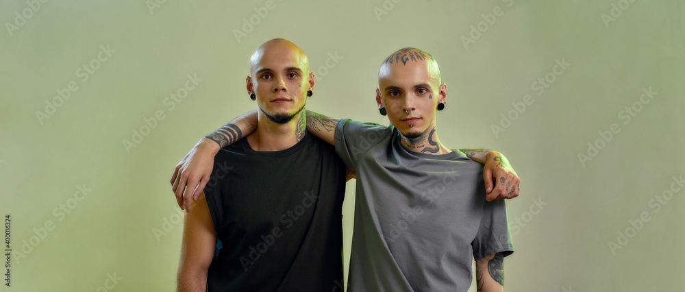Real friends. Horizontal shot of two young twin brothers with tattoos ...