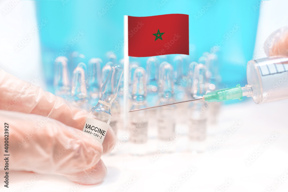 Hands holding a vaccine vial and a syringe with rows of the same ...