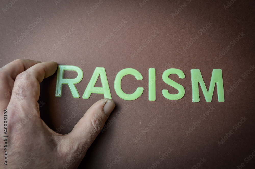 Human fingers removes the word Racism written with plastic letters on a ...