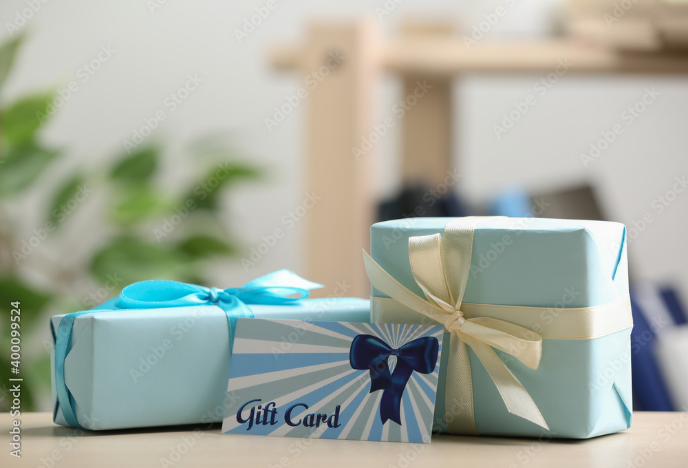 Gift card and present on table against blurred background, space for ...