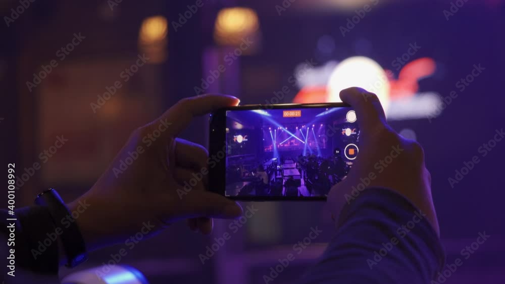 Hands holding smartphone to take VDO of stage concert with colorful ...