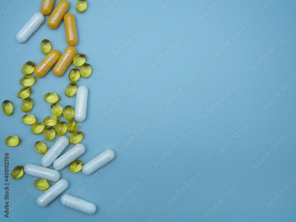 Assorted vitamins capsules on a light blue background with copy space ...