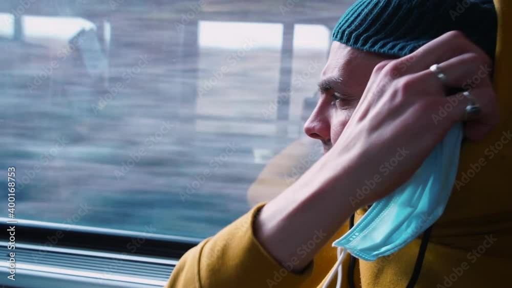 Male passenger rides a train on a seat and takes off his mask ...