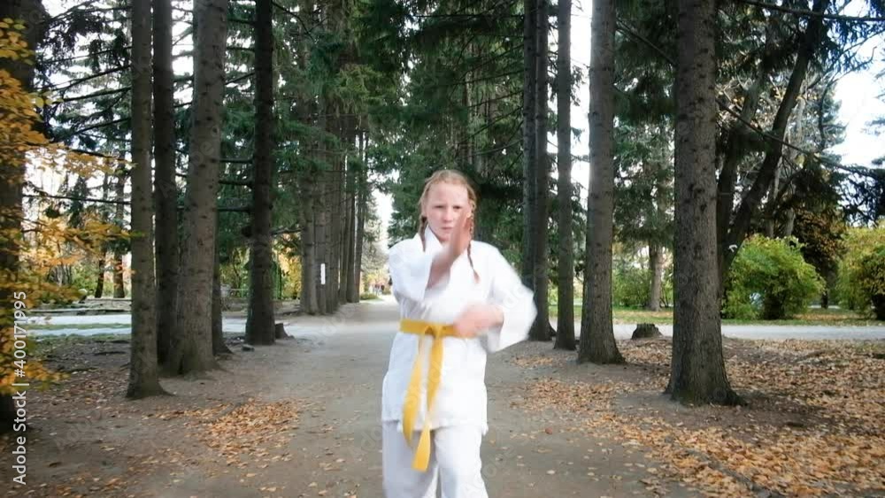 teenager girl 12 years old is engaged in karate outdoors in the park ...