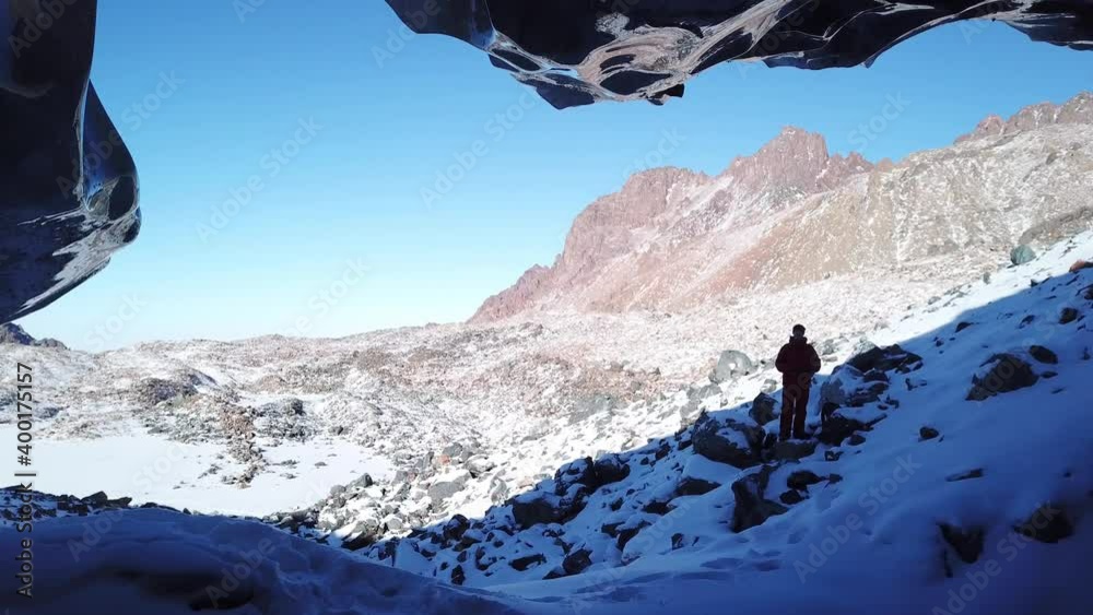 The guy explores the ice cave. a dangerous place. Thick ice shimmers ...