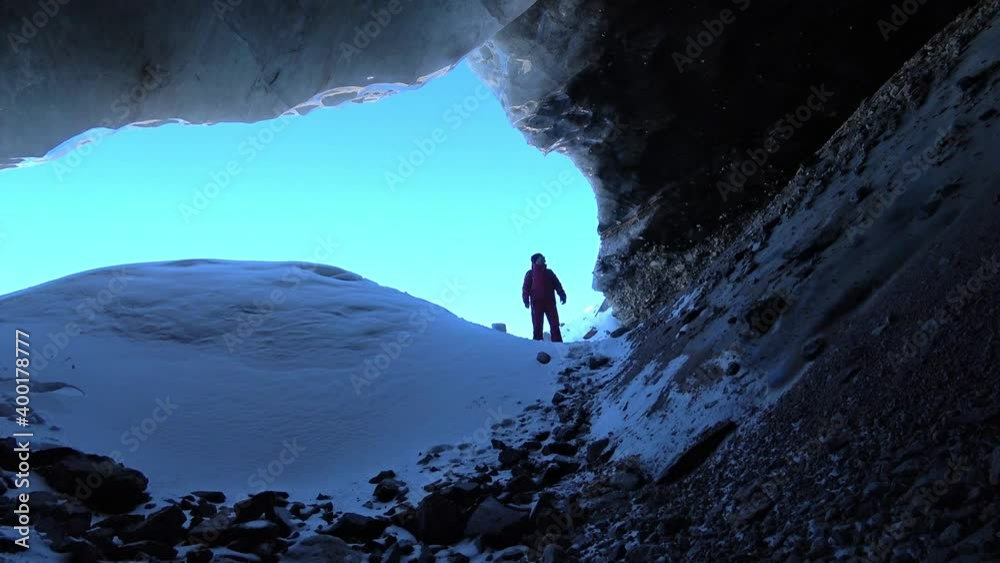 The guy explores the ice cave. a dangerous place. Thick ice shimmers ...