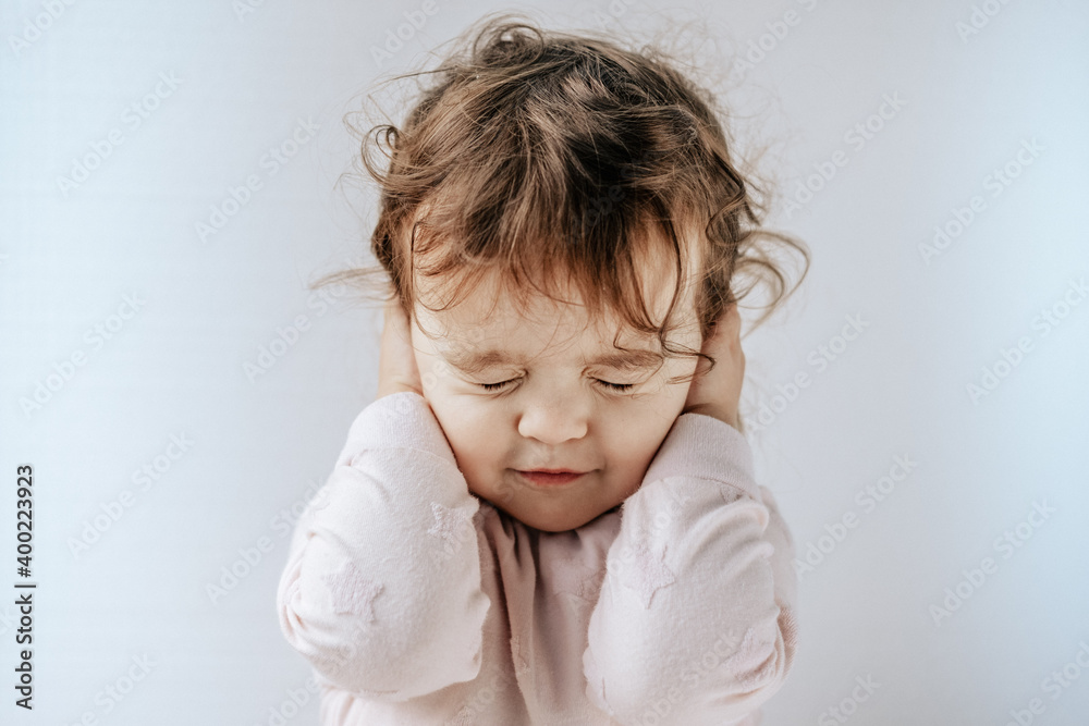 a child on a white background covered his ears with his hands, afraid ...