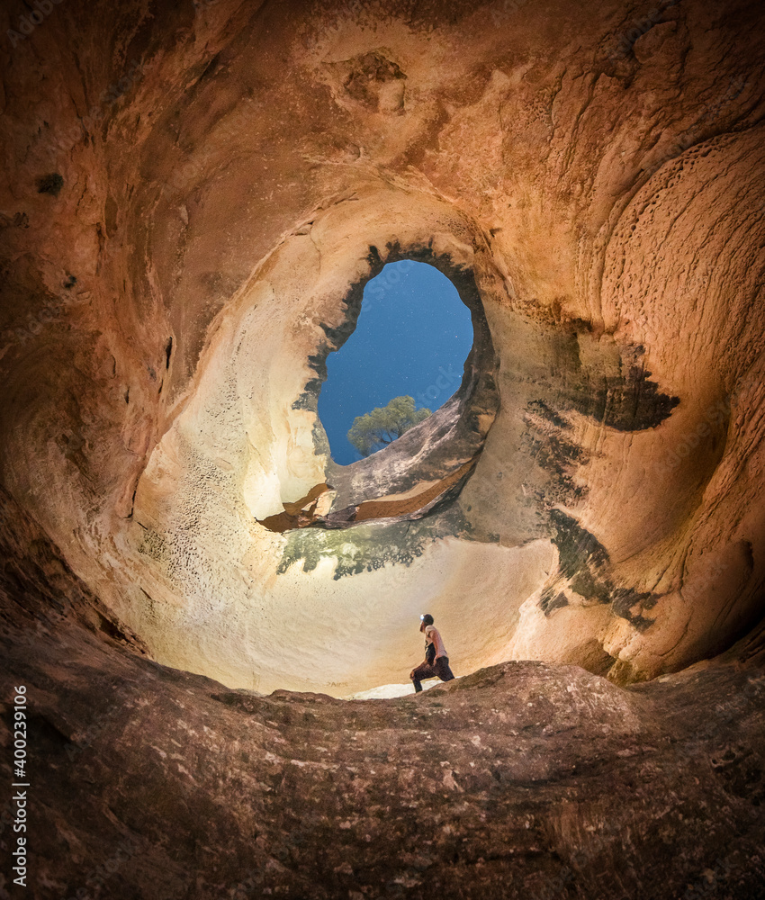 A man shines his flashlight inside a large cave. A large cavern with a ...