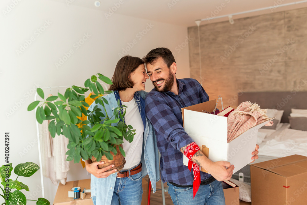 Couple in love hugging and carrying boxes while moving in new home ...