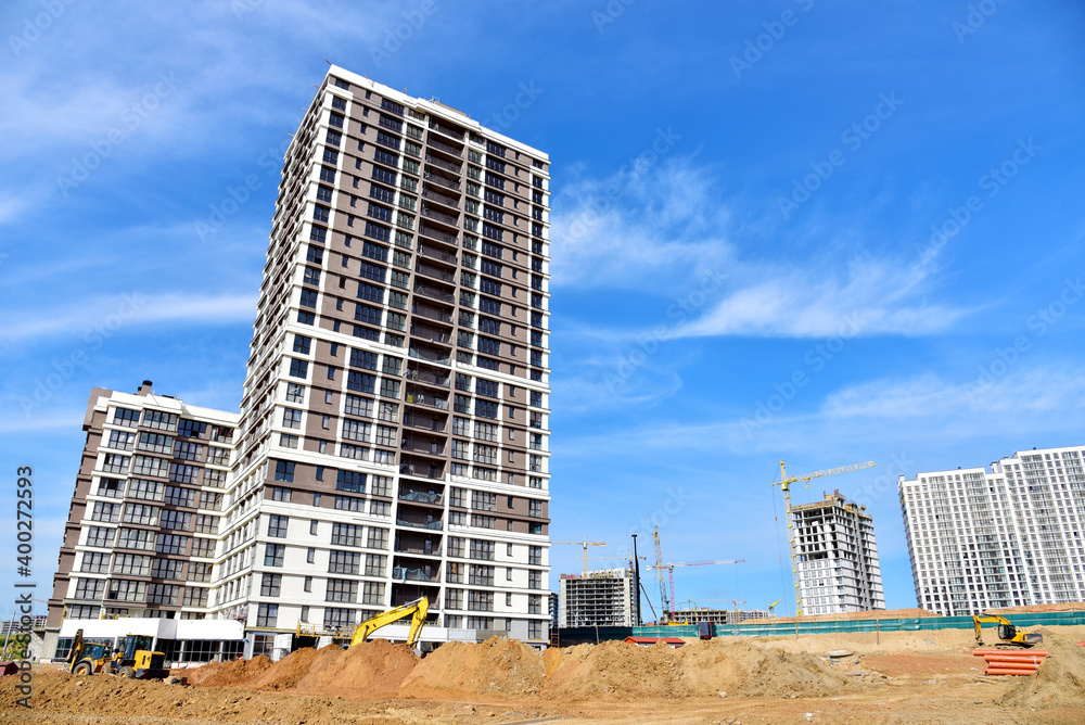 Tower cranes in action on blue sky background. Excavator dig ground for ...