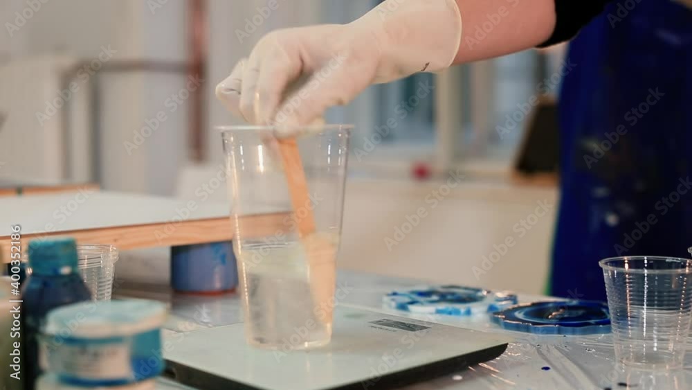 Mixing a clear liquid in a glass on a scale. Prepare the epoxy material ...