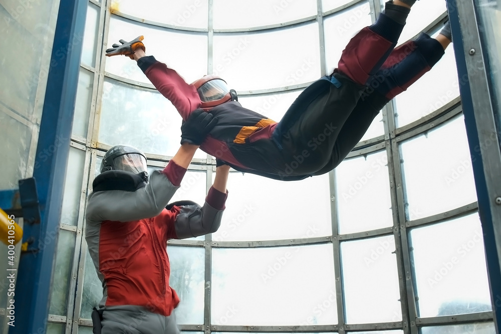 Child boy with man instructor flying in aerodynamic tube, professional ...
