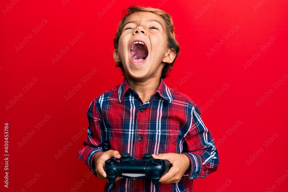 Adorable latin kid playing video game holding controller angry and mad ...