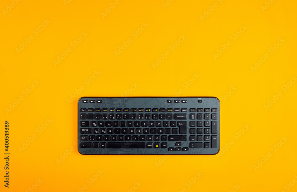 Black computer keyboard on yellow background with copy space. Overhead ...