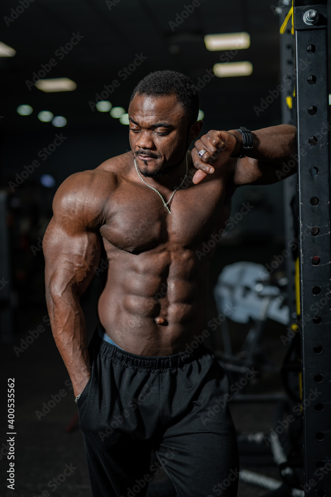 Black model bodybuilder poses to the camera in modern gym. African ...