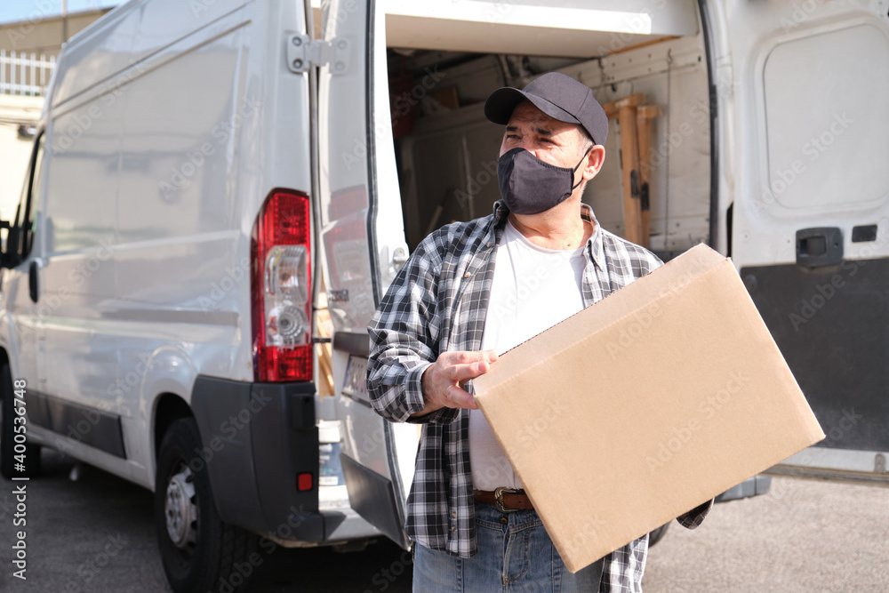 Delivery senior man standing in front of his van holding a package ...