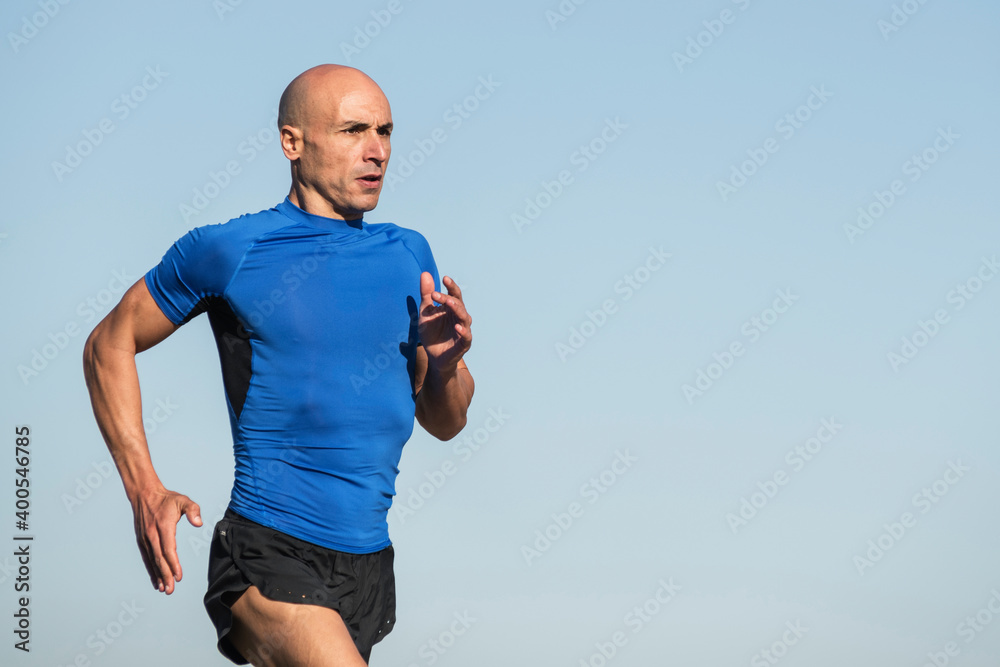 Adult man with a shaved head and sportswear running with an expression ...