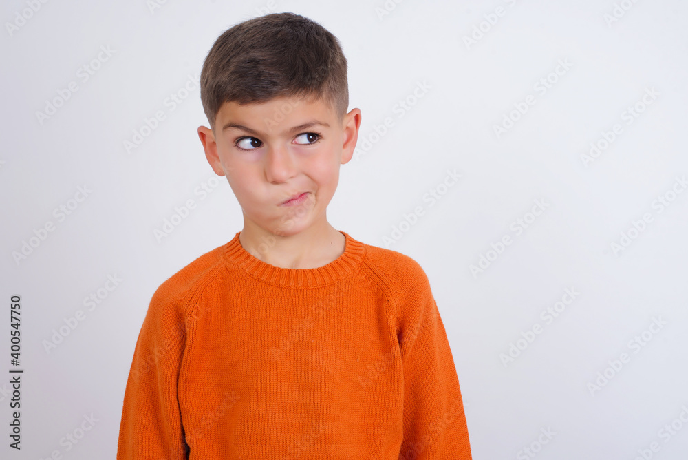 Cute Caucasian kid boy wearing knitted sweater against white wall ...