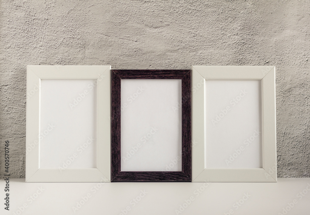Three empty photo frames in a dark and light frame on a table or shelf ...