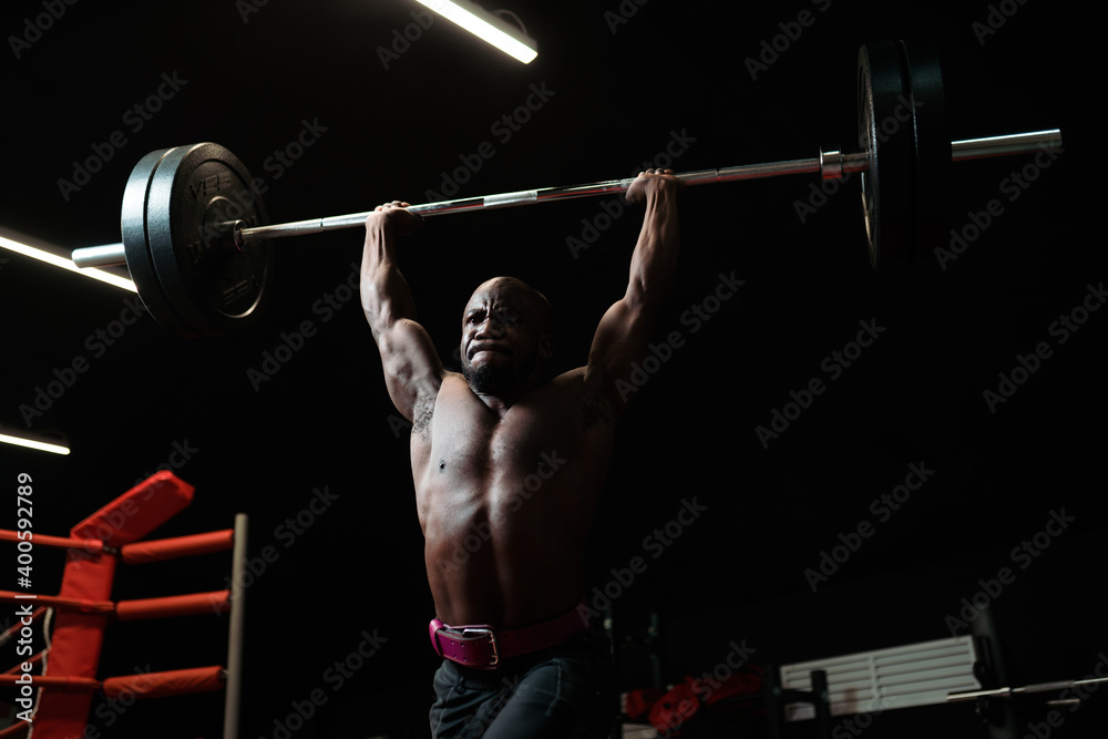 Heavyweight man training with a barbell. Bodybuilding trainer lifts ...