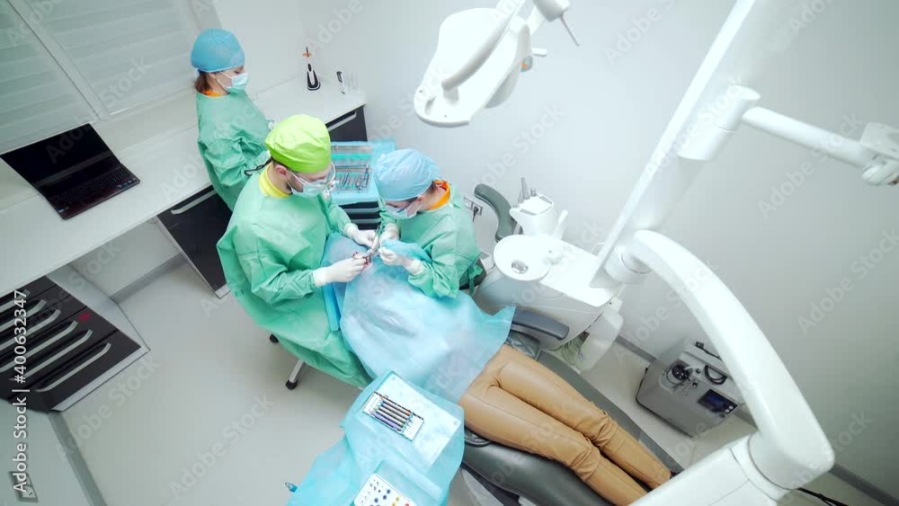 Team of dental surgeons performs surgery on teeth. in a modern clinic ...