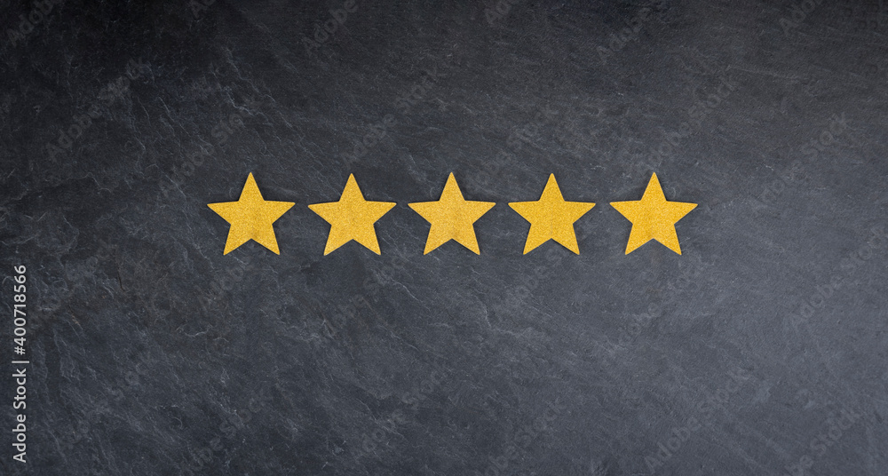 Five golden, glittering stars on a slate background as a symbol for a ...