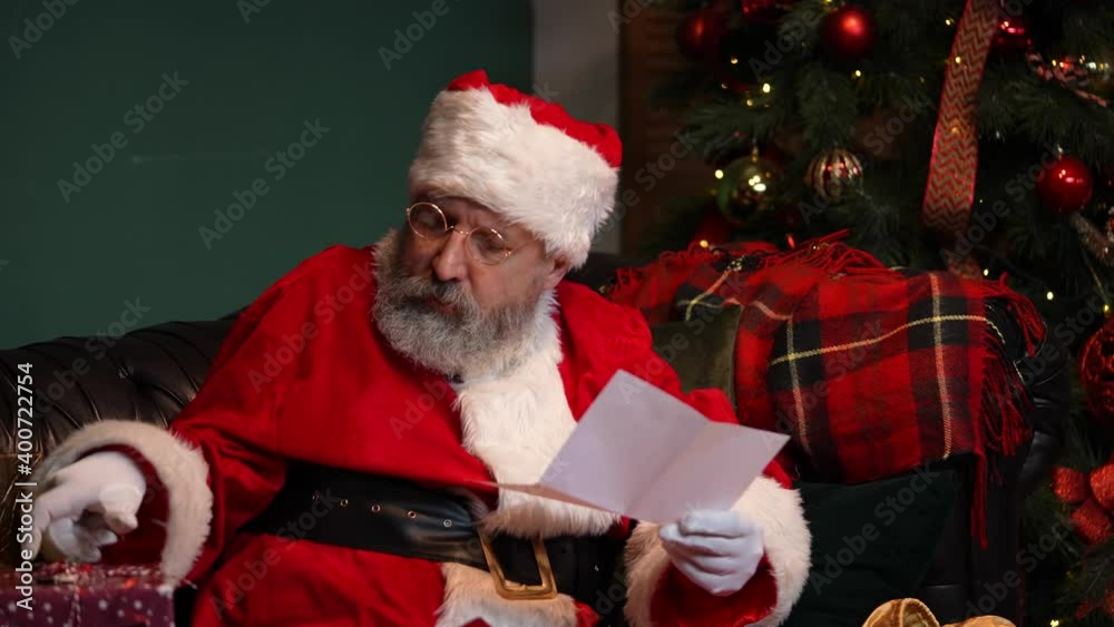 Santa Claus reads letters and chooses gifts for children. Old man in a ...