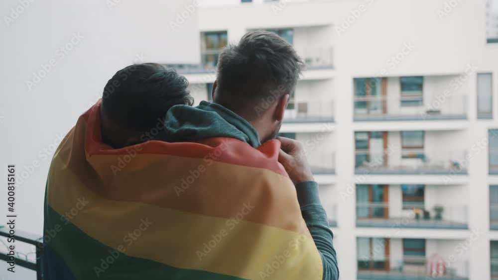 Young homosexual couple enjoying the view from the balcony covered with ...
