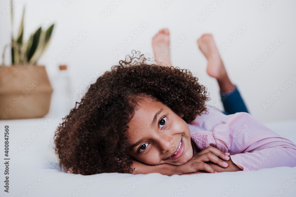 Little girl lying on front in bedroom at home Stock Photo | Adobe Stock